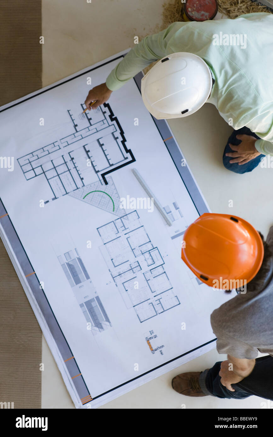 Two men crouching looking over blueprints spread out on floor Stock ...