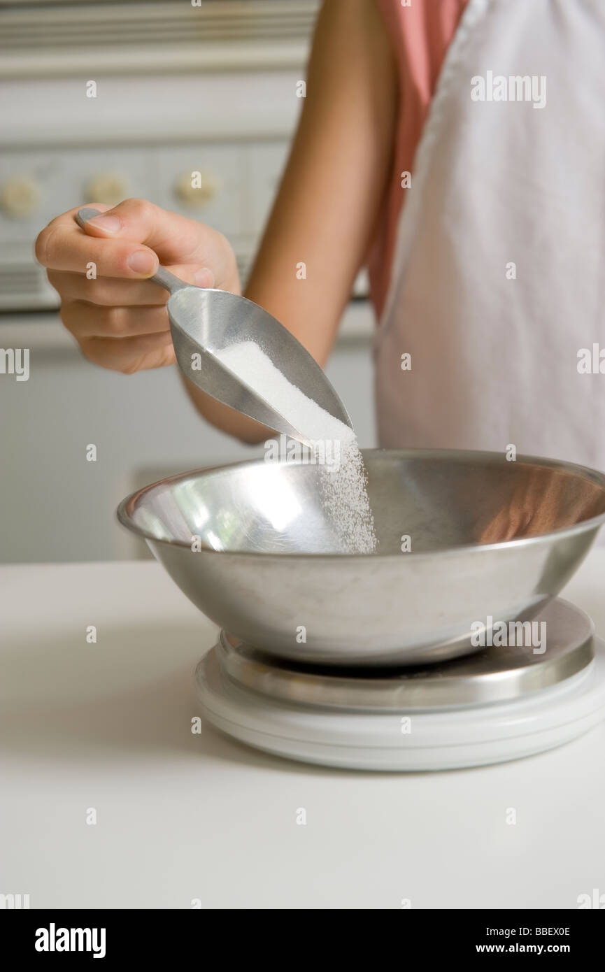 Young girl pouring sugar into metal bowl Stock Photo - Alamy