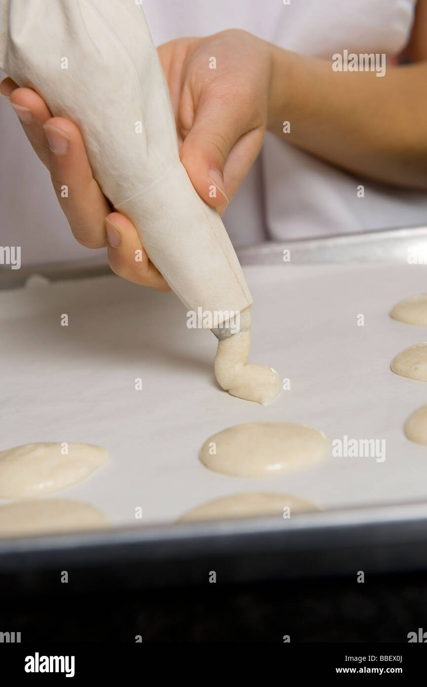 Young girl piping cookies on to parchment paper Stock Photo - Alamy