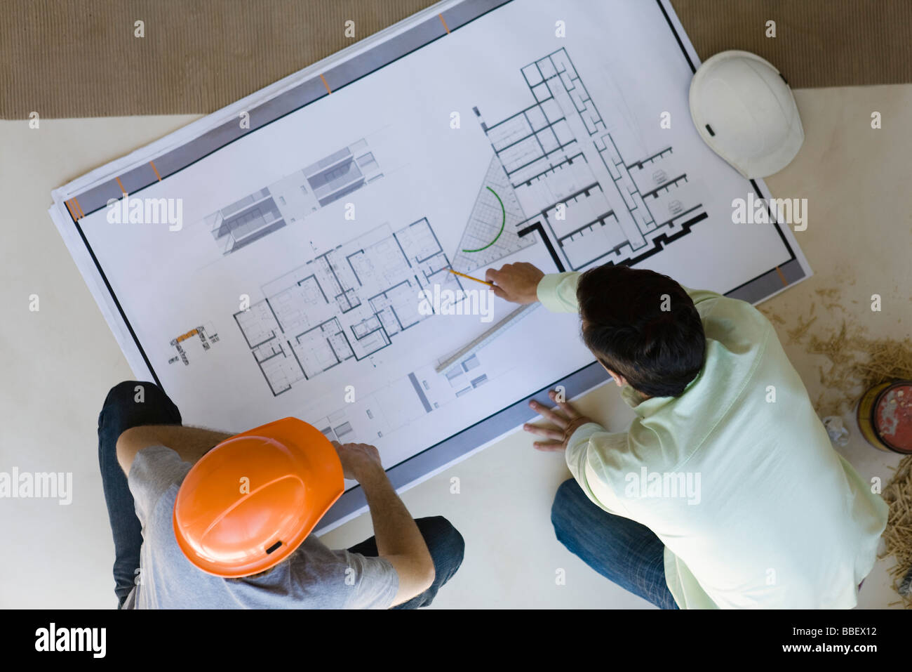 Two men side by side reviewing blueprint spread out on floor Stock ...
