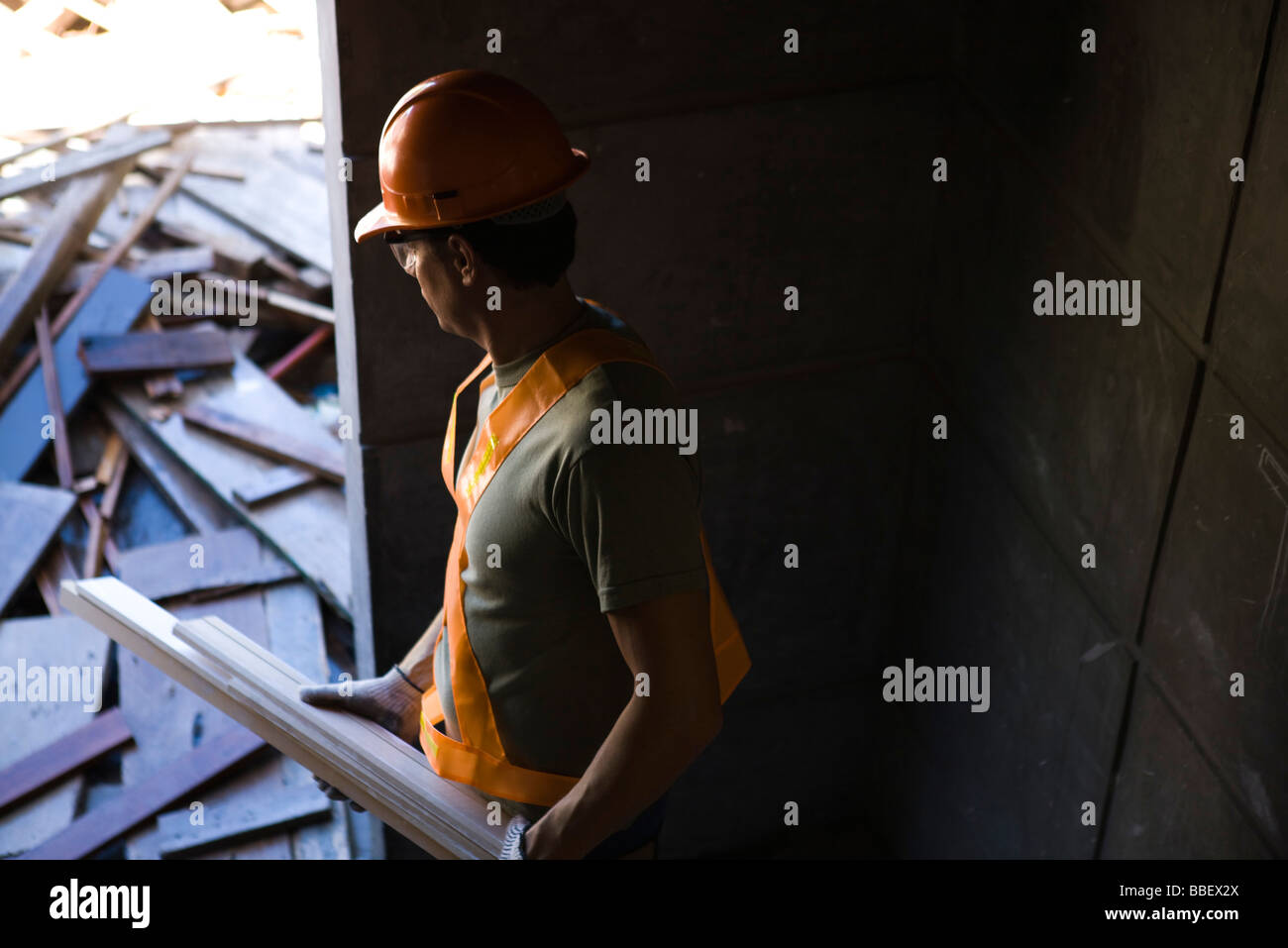 Construction worker carrying scrap wood cleaning up construction site ...