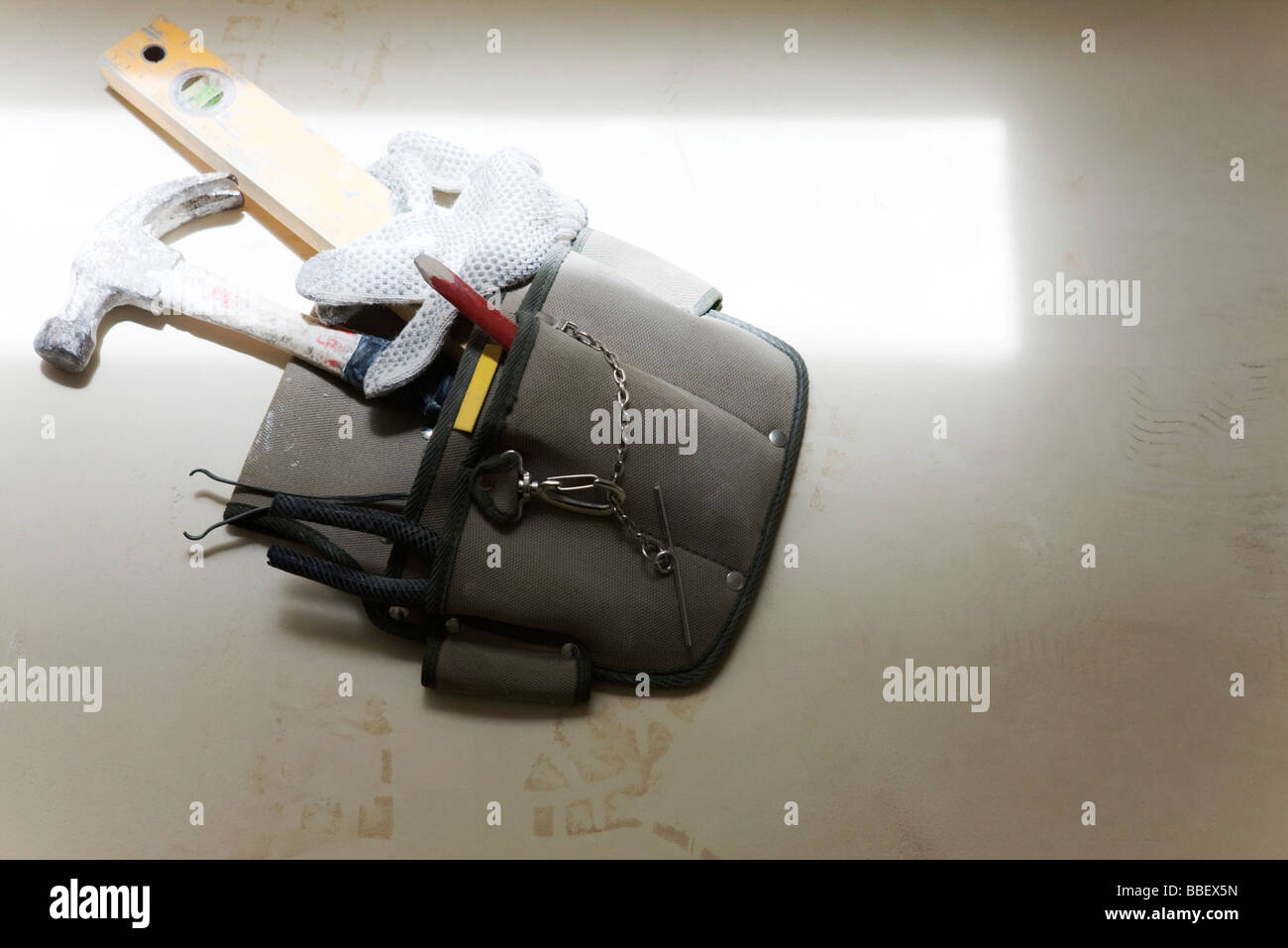 Tool belt with hammer, level and gloves lying on floor Stock Photo - Alamy