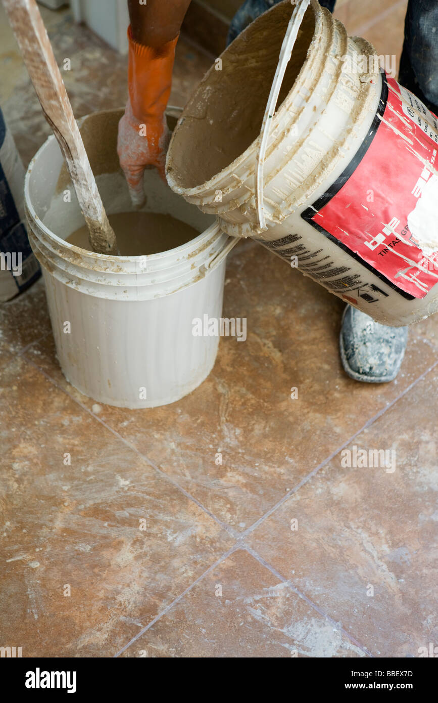 Worker pouring plaster from one bucket to another Stock Photo - Alamy