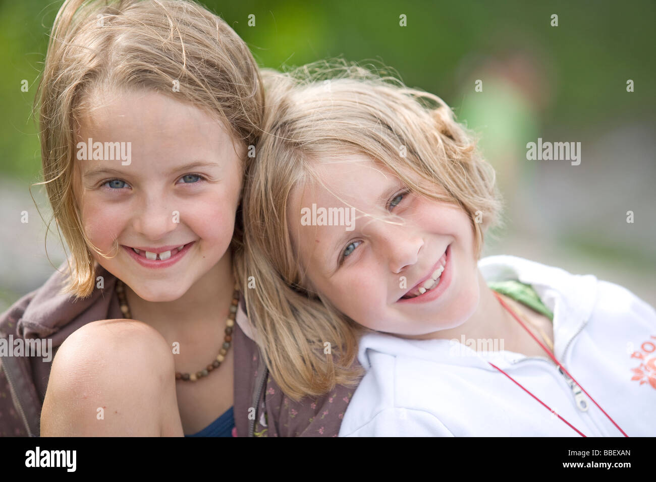 Two girls sitting beside each other Stock Photo - Alamy