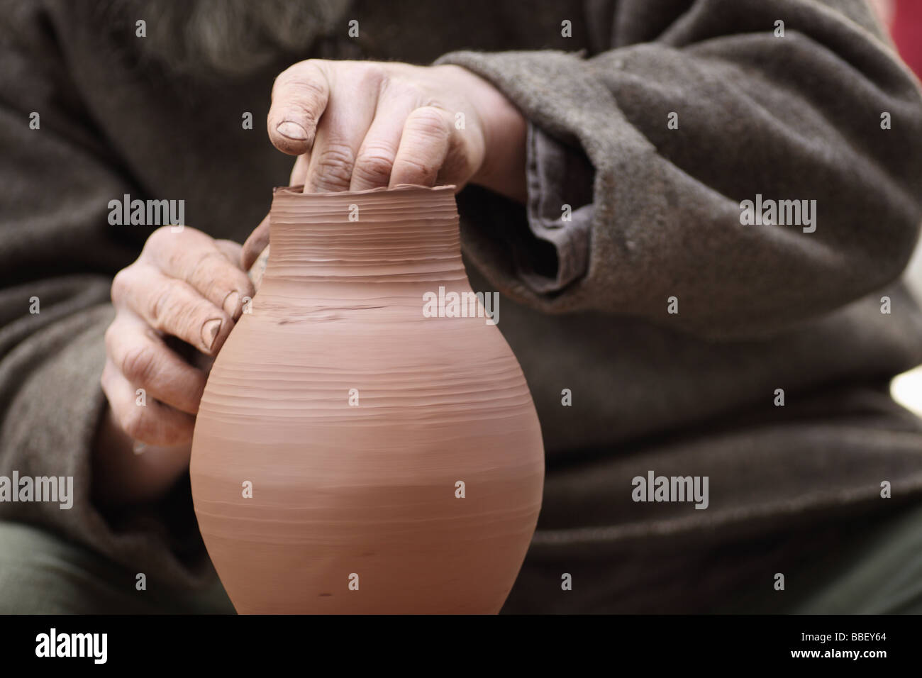 An artist making a clay pot in the traditional method on a potters ...
