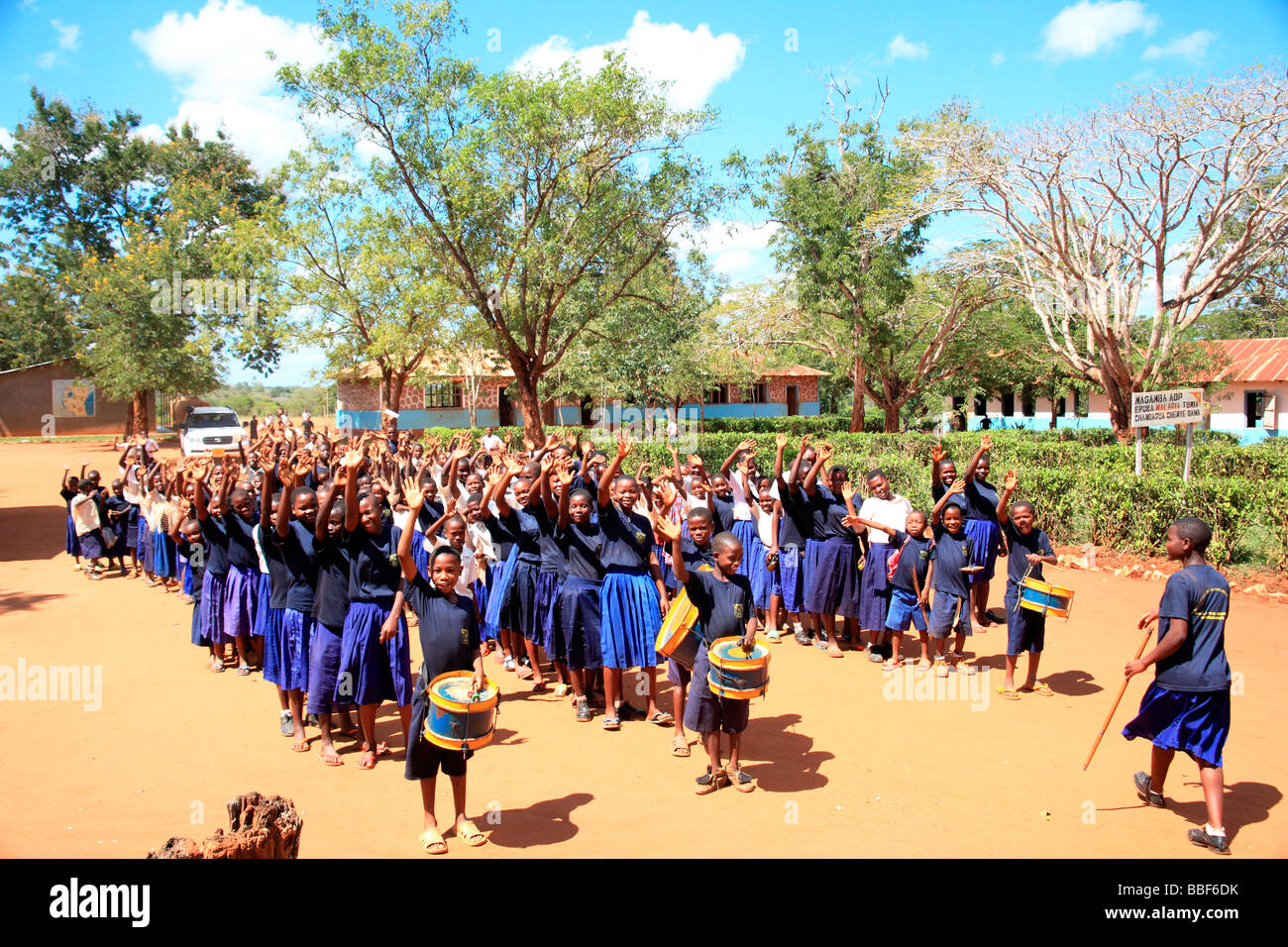 Tanzanian village school children prepare for a parade and wave to the ...