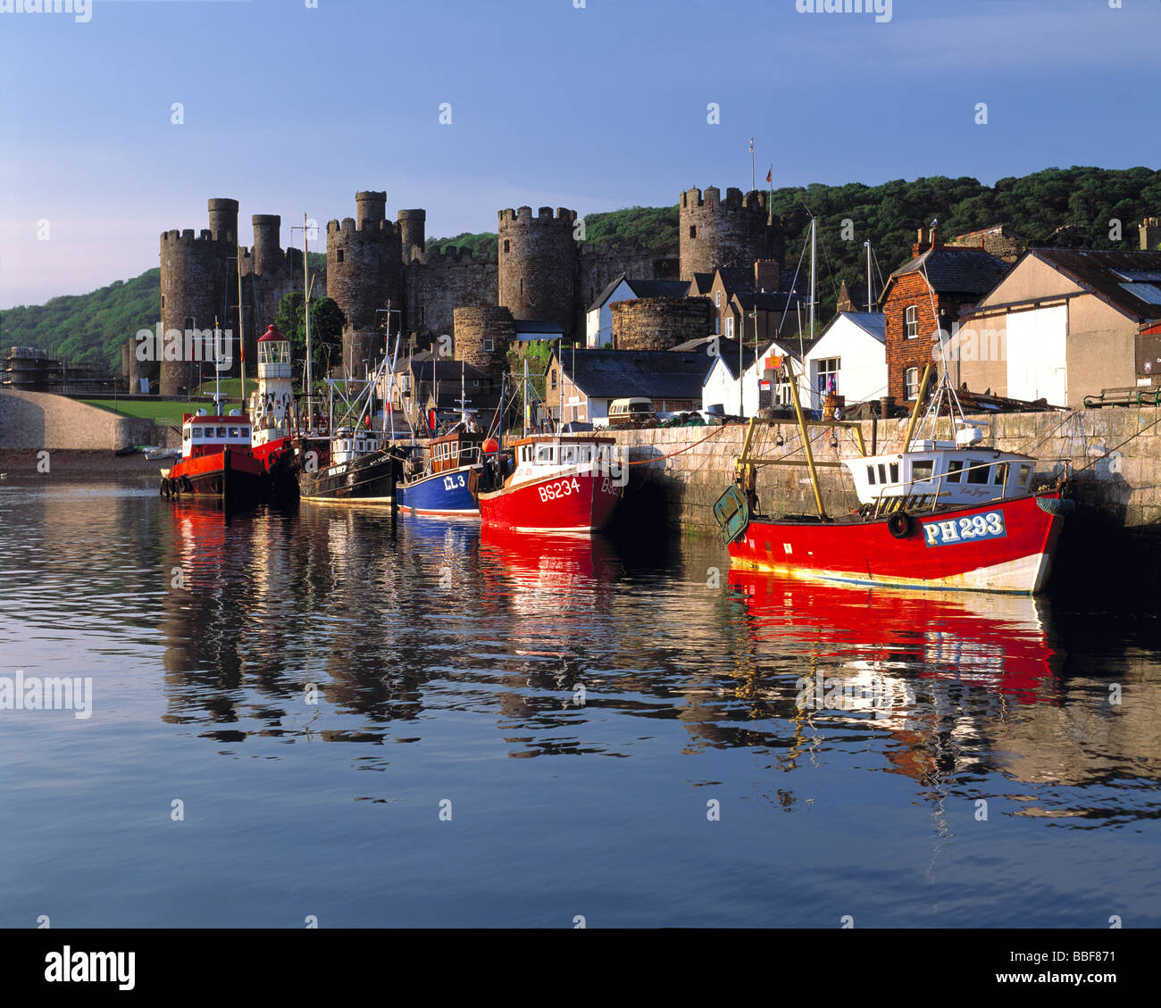 Fishing boats reflect in the peaceful arbor near the Castle in Conwy ...