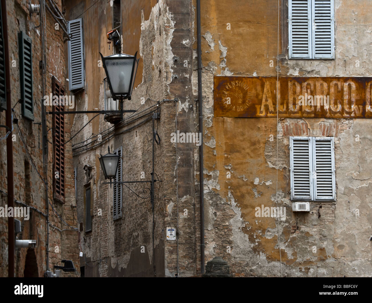 Old fashioned rusting sign on a peeling plaster wall in Siena, Tuscany ...