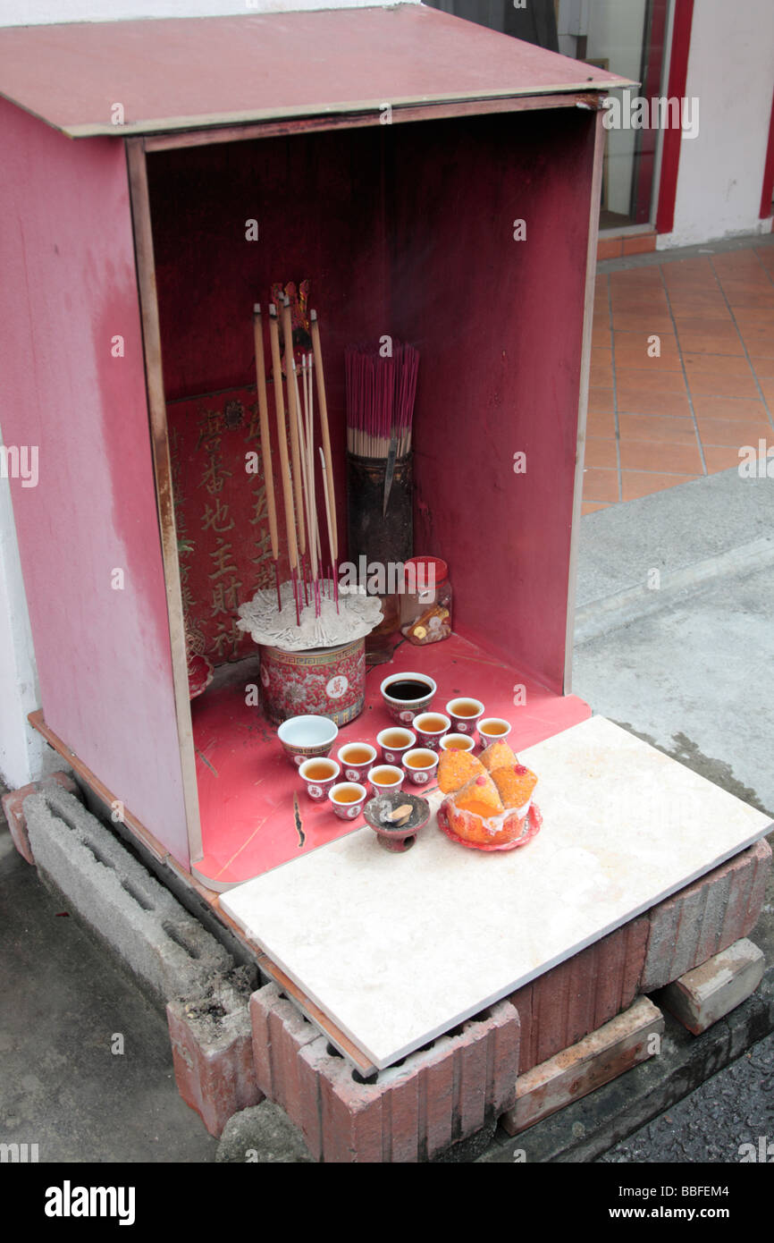 A small altar in the street with offerings of tea and incense in ...