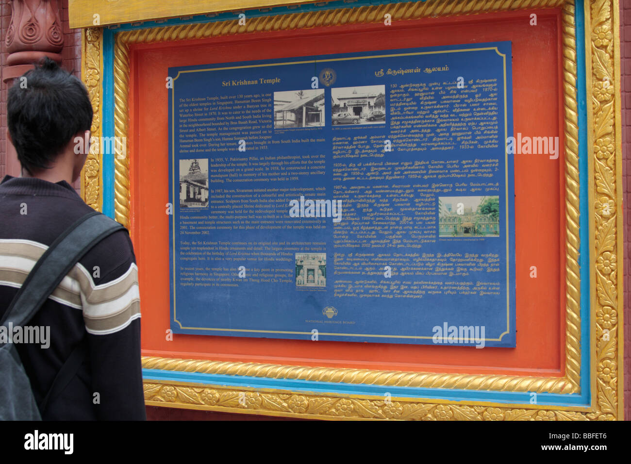 A man reading the story of the Sri Krishnan Temple displayed outside in ...