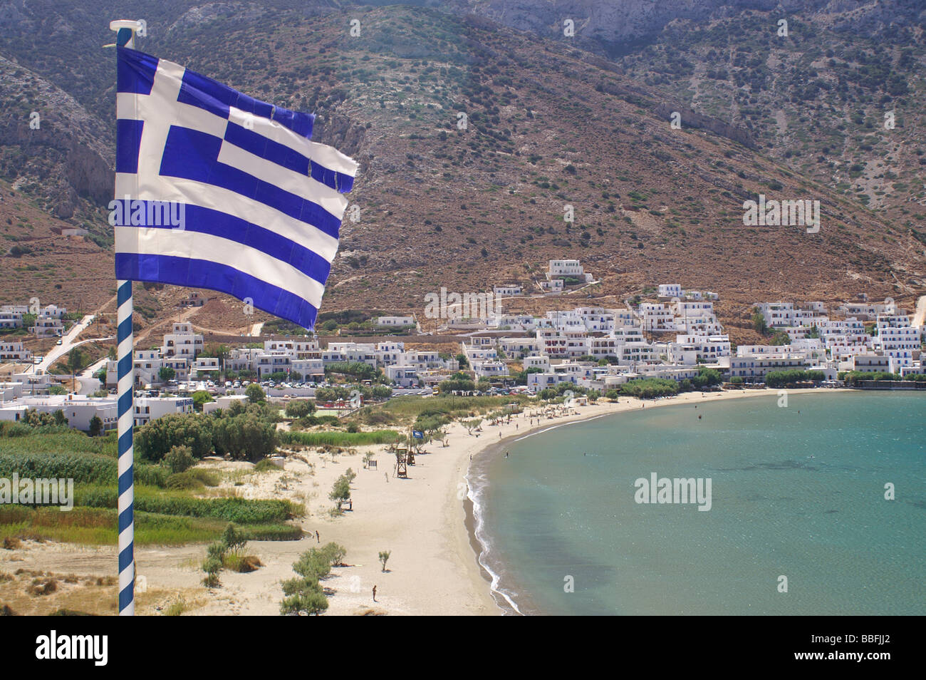 The greek flag flies over the shore of a small island in the Cyclades ...