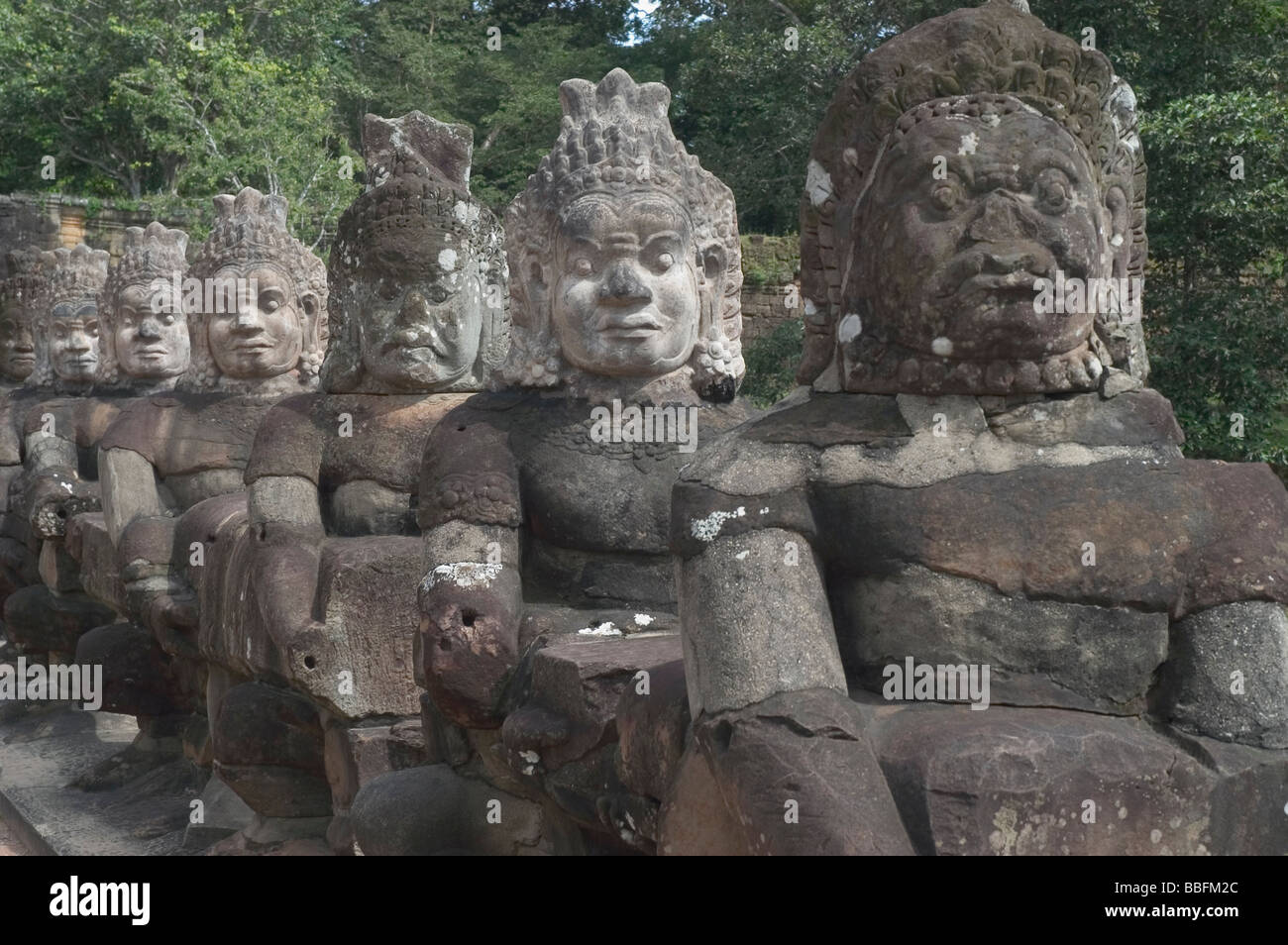 Stone demon faces on the naga bridge at the south gate of Angkor Thom ...