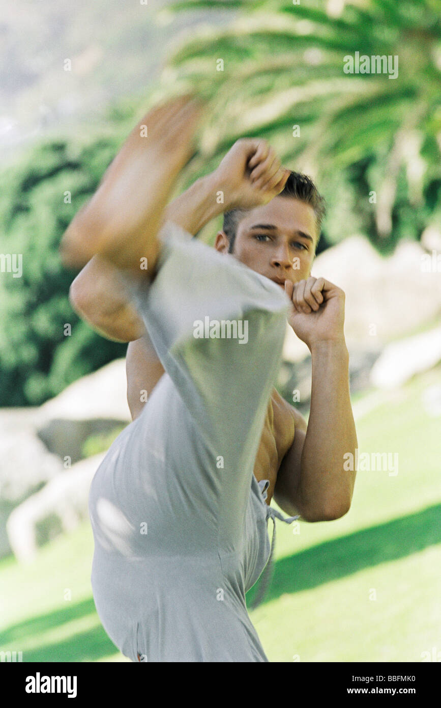 Male practicing martial arts kick in park setting, front view Stock ...