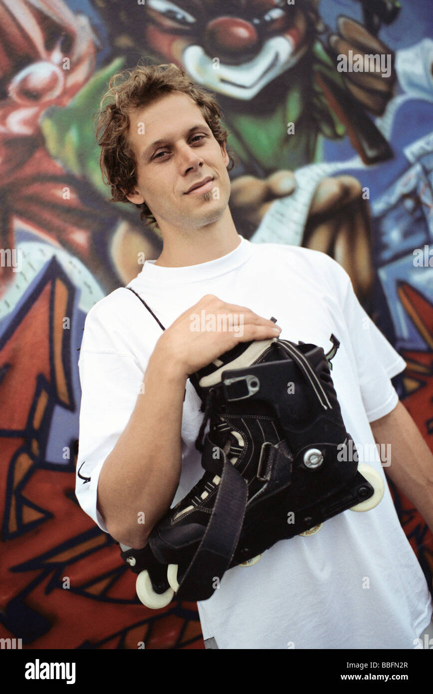 Male with pair of inline skates hanging over shoulder standing in front ...
