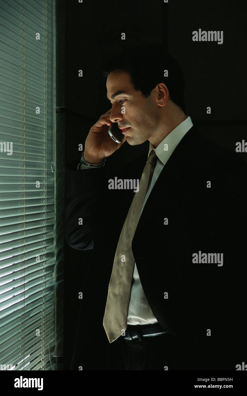 Businessman using cell phone, looking through blinds out window Stock ... Businessman using cell phone, looking through blinds out window Stock ...