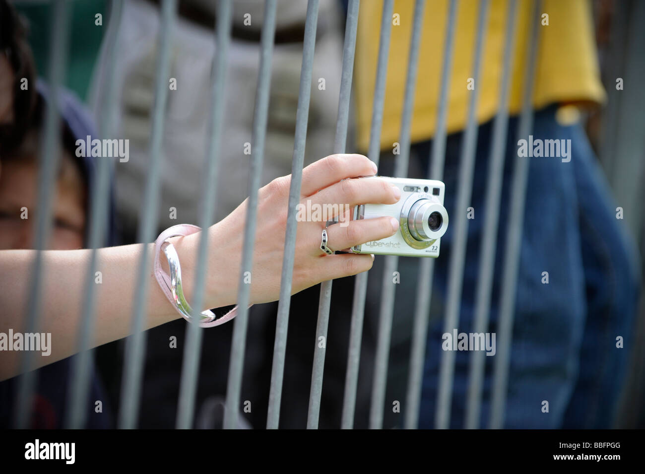 A small digital camera is pushed through crowd barriers to take a ...