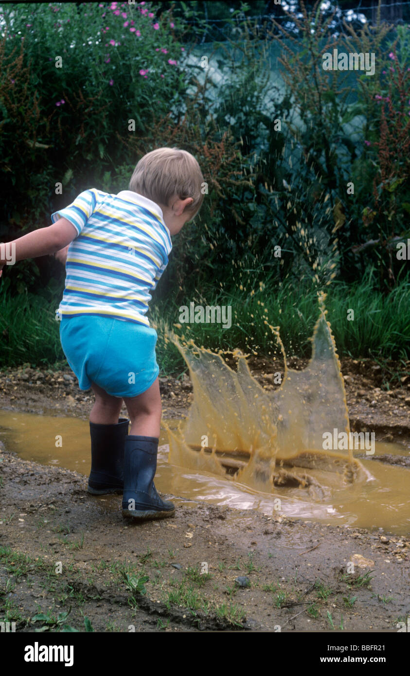 Child hitting a Puddle with a stick Stock Photo - Alamy