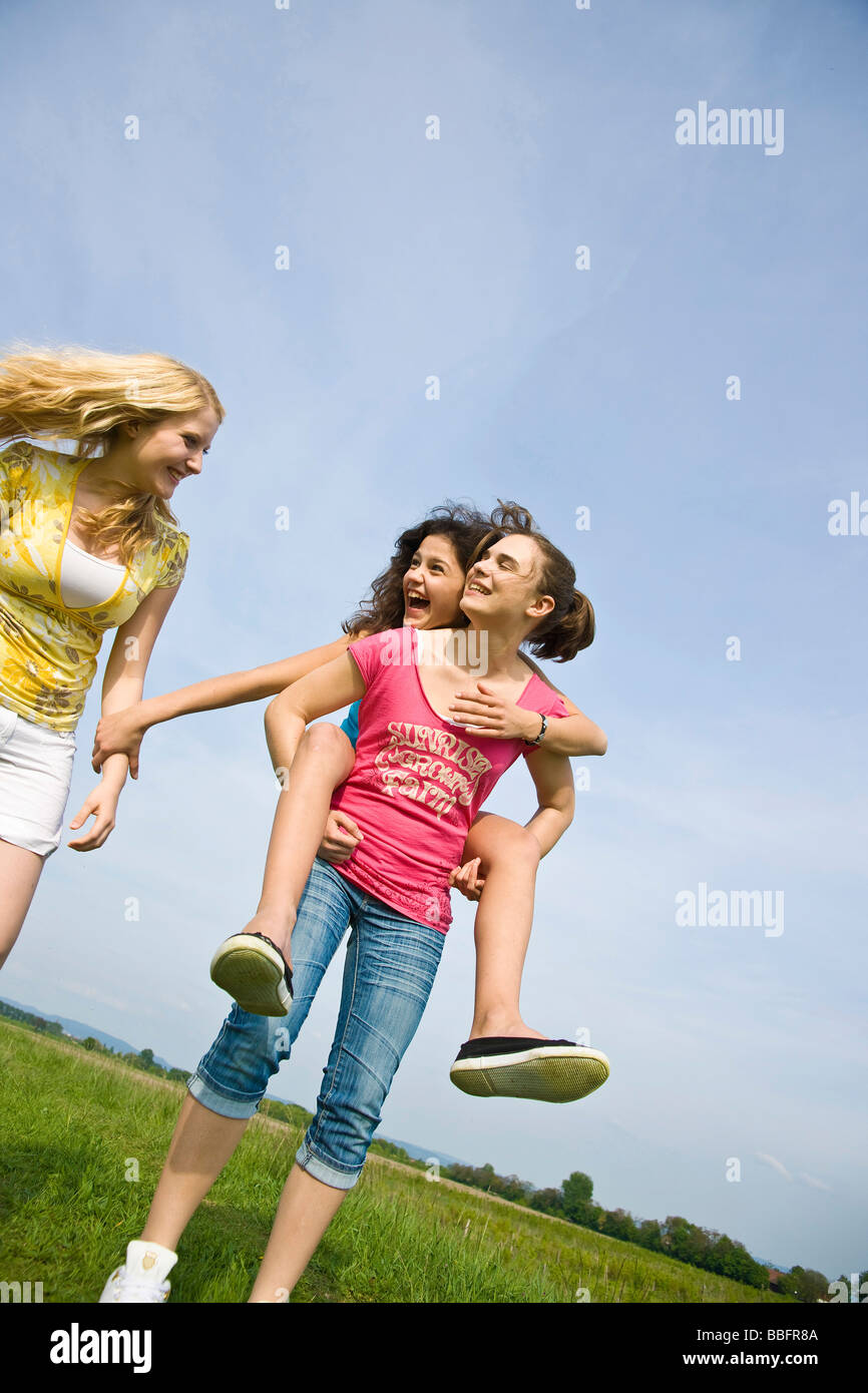 Three smiling girls strolling happily over a meadow Stock Photo - Alamy