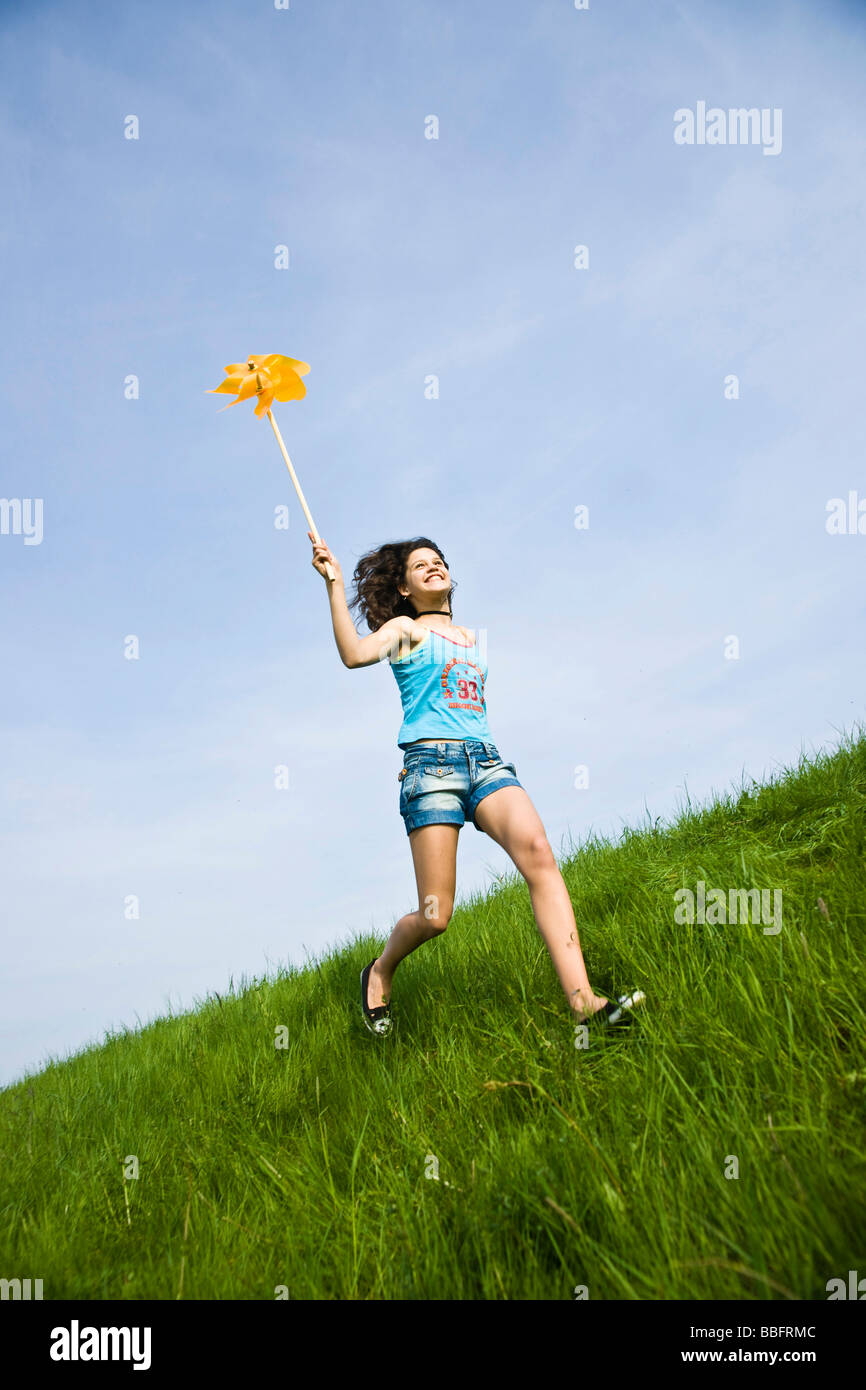 Girl running over a meadow holding a pin wheel Stock Photo - Alamy