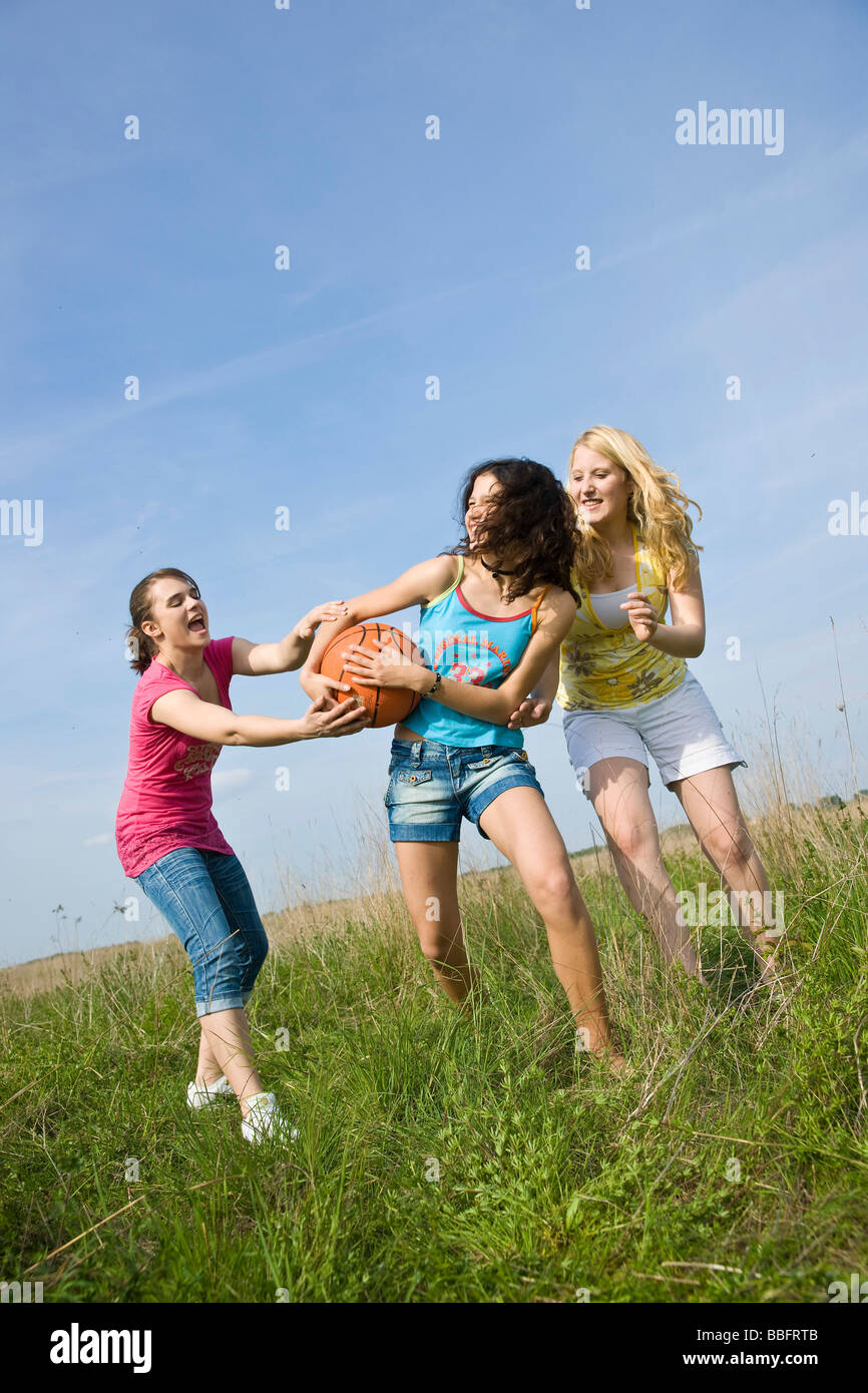 Three girls playing with a basketball on a meadow Stock Photo - Alamy