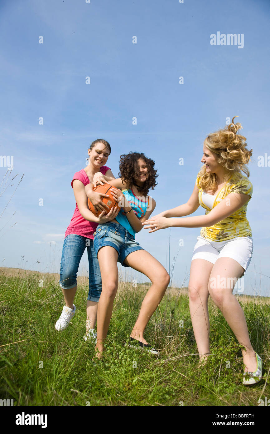 Three girls playing with a basketball on a meadow Stock Photo - Alamy