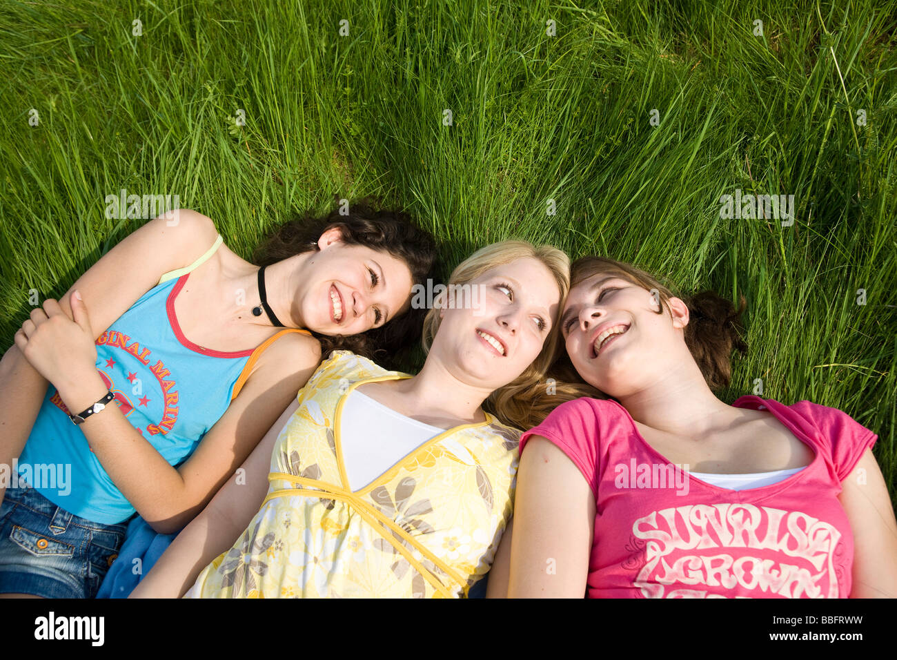 Three smiling girls lying in the grass, smiling Stock Photo - Alamy