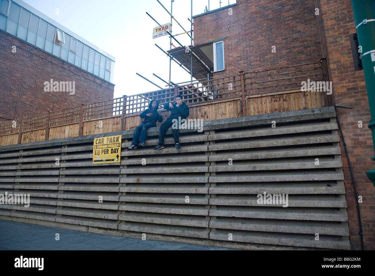 Two teens sitting above a building construction, eating ice cream and ...