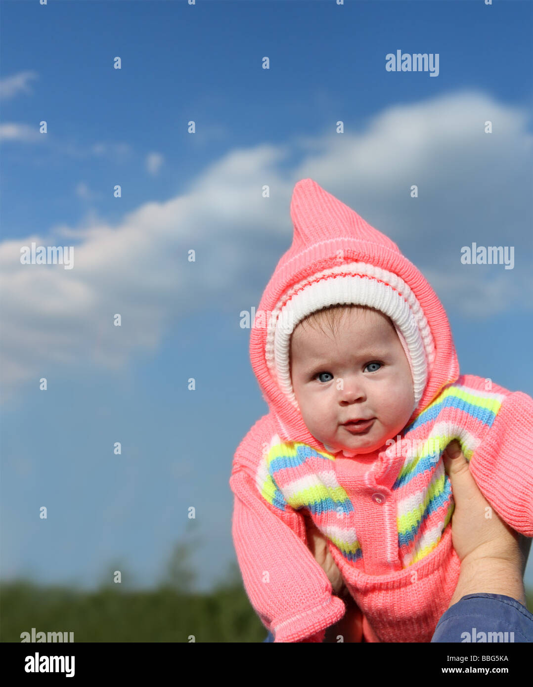 baby in pink hood on blue sky background Stock Photo - Alamy