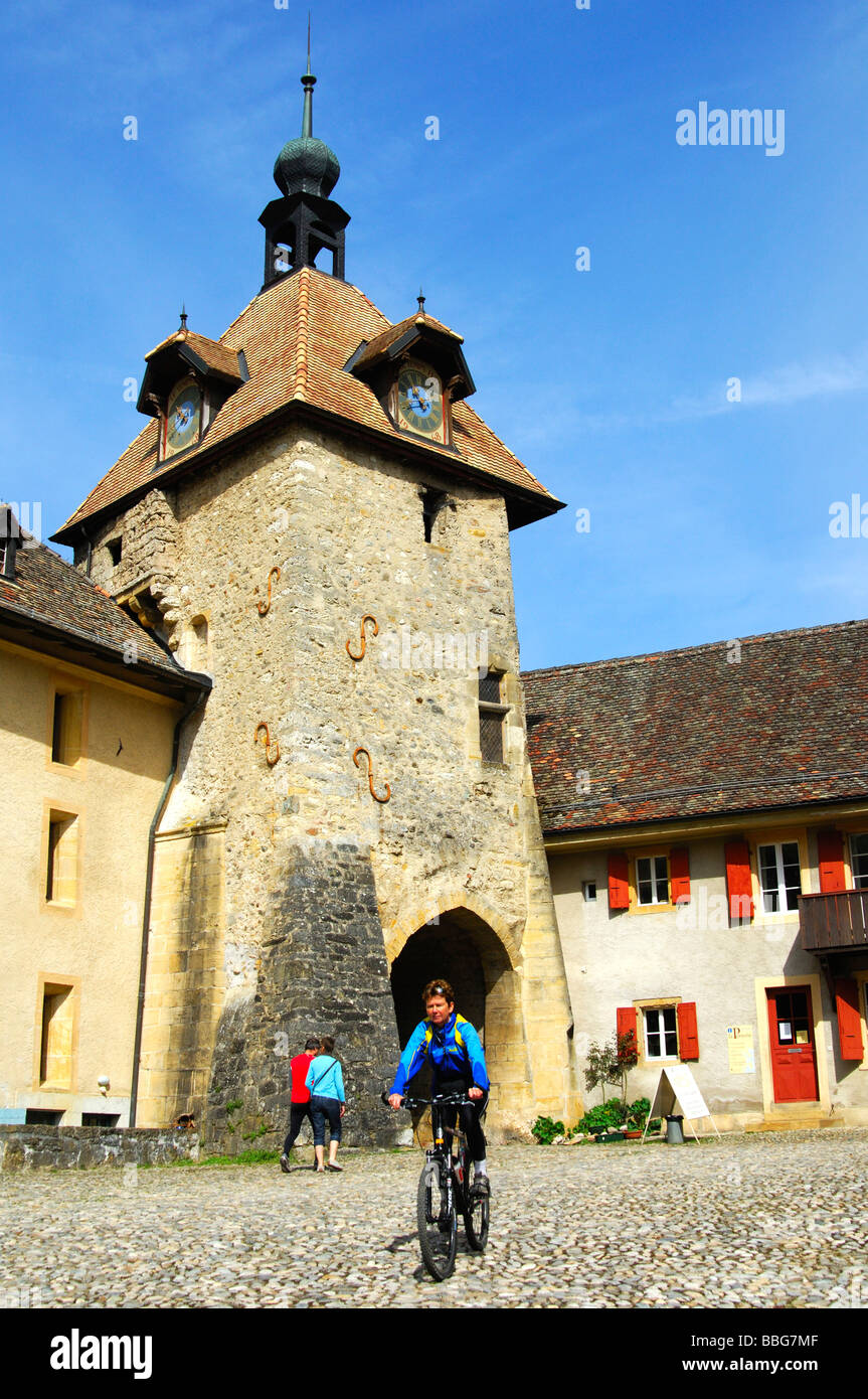 Cyclist entering the courtyard of the Romanesque abbey Romainmoitier ...