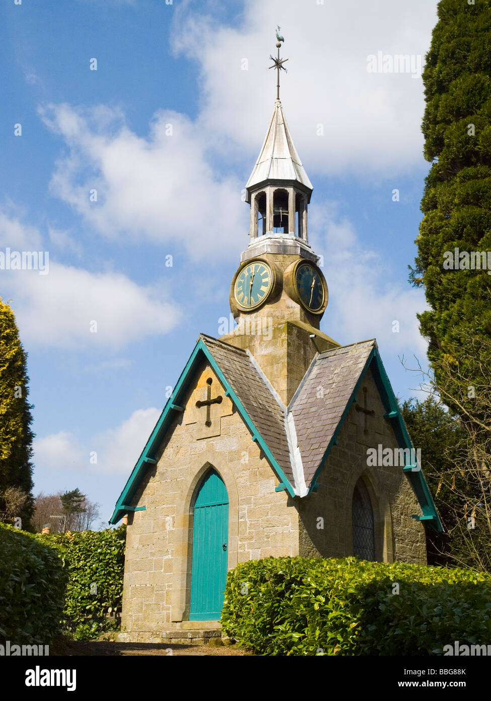 A small stone church building with a clock tower and weather vane ...