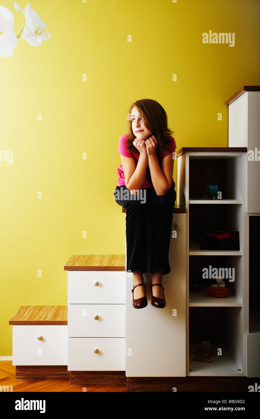 Young girl sitting on the steps of a chest of drawers Stock Photo - Alamy