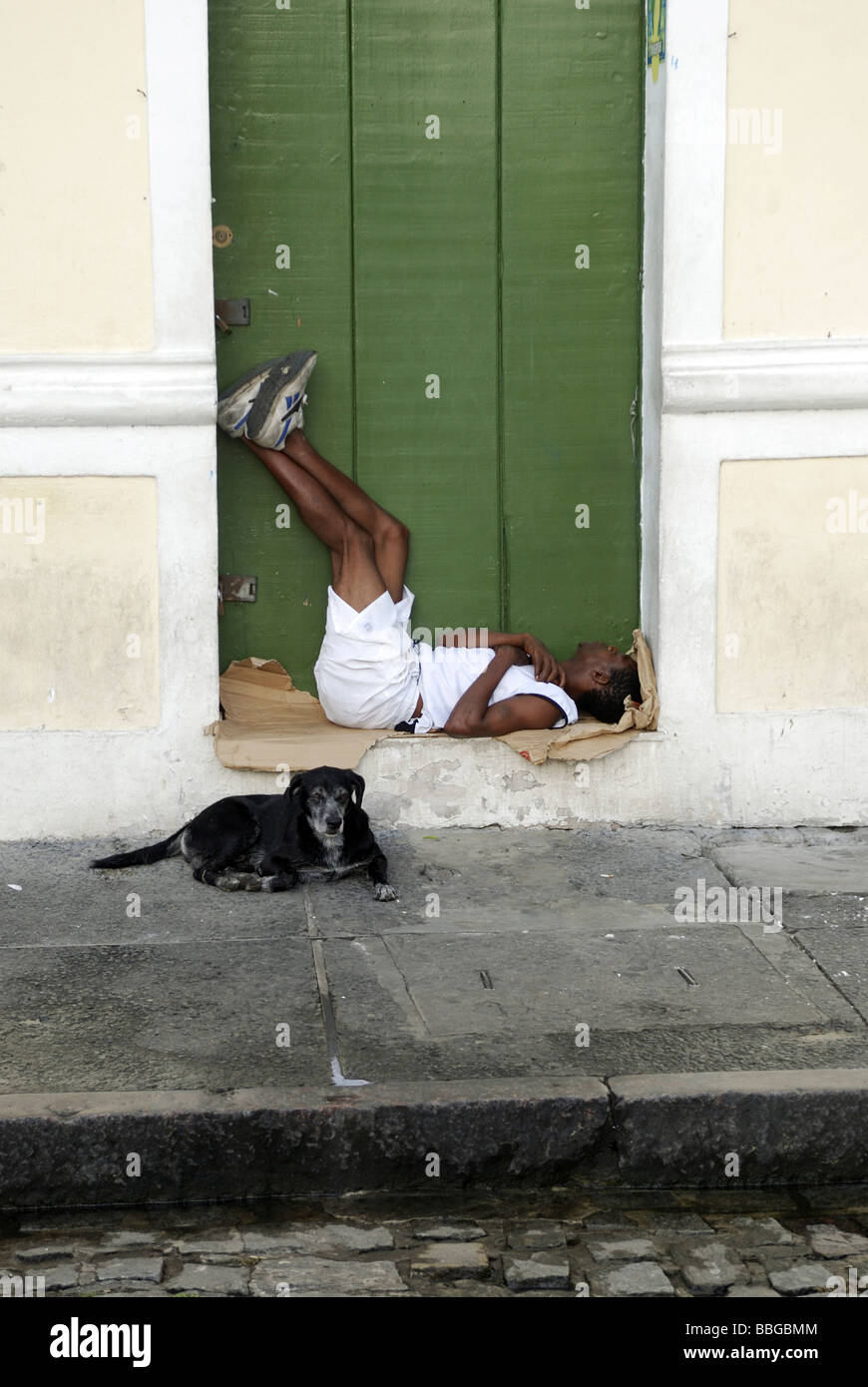 Homeless man sleeping in a house entrance guarded by his dog, Salvador ...