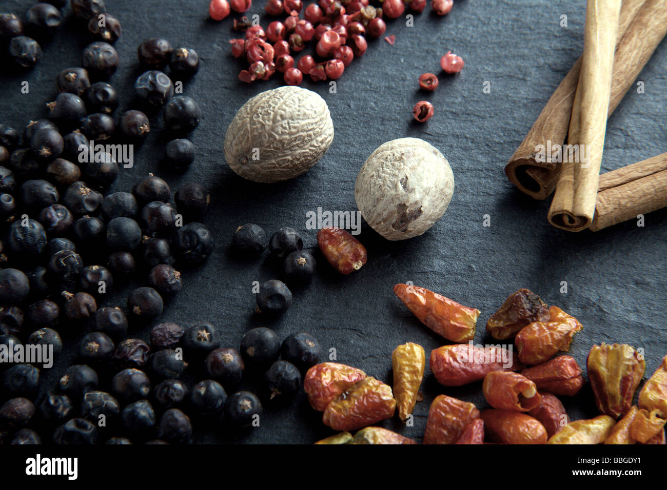 Different spices on a slate, juniper, chili peppers, red pepper, nutmeg ...