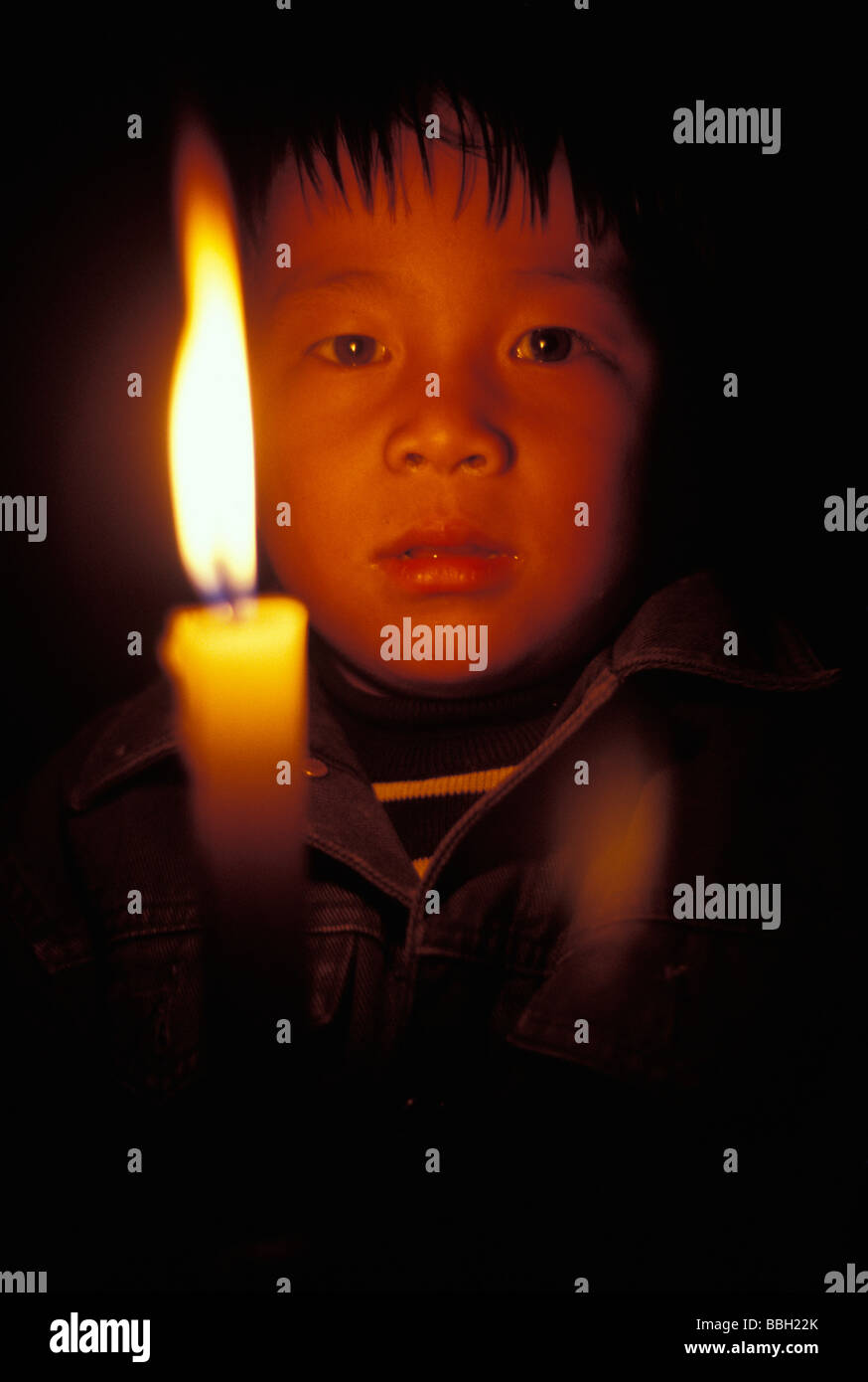 Young child behind lit candle Stock Photo - Alamy