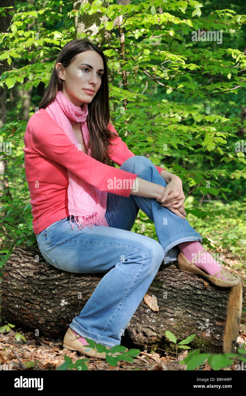 Young woman sitting on tree log hi-res stock photography and images - Alamy