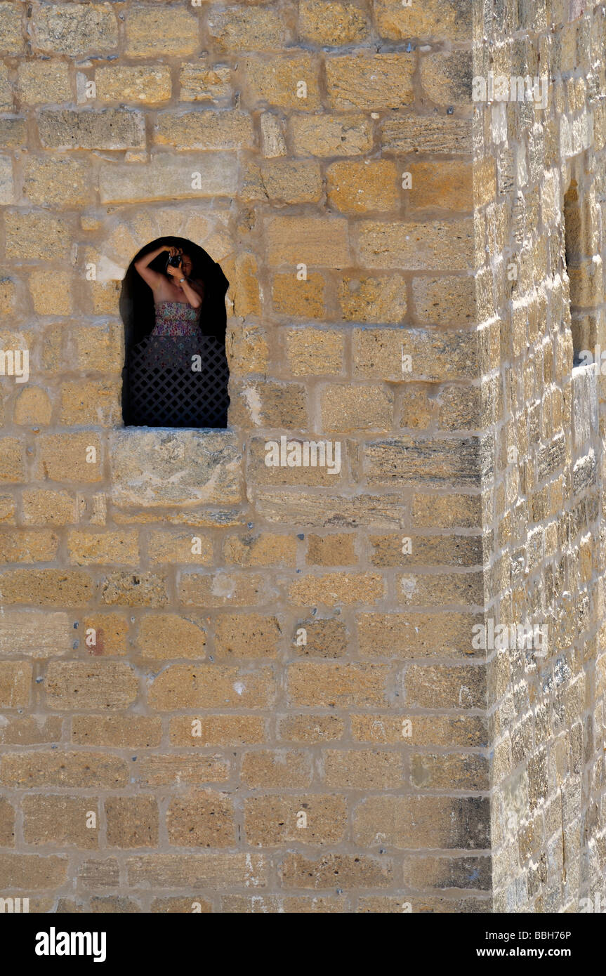 Woman with camera looking out of small window of stone tower Stock ...