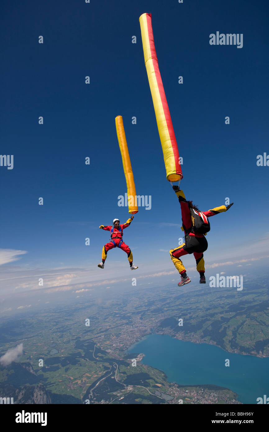 Skydivers are flying head up with a air tube in there hands over a ...