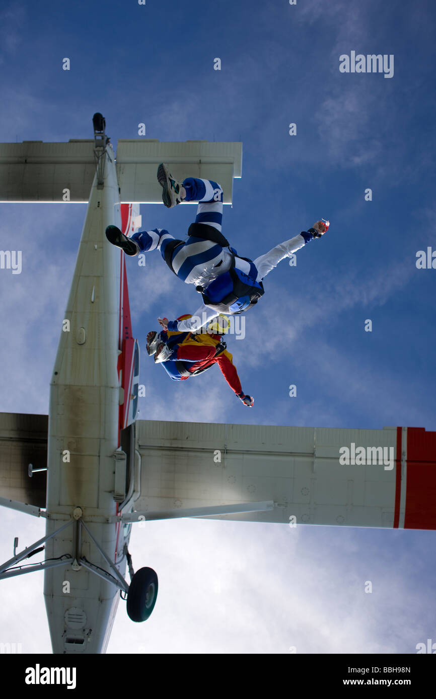 Skydivers are exiting a plane as a team in the sit fly position. They ...