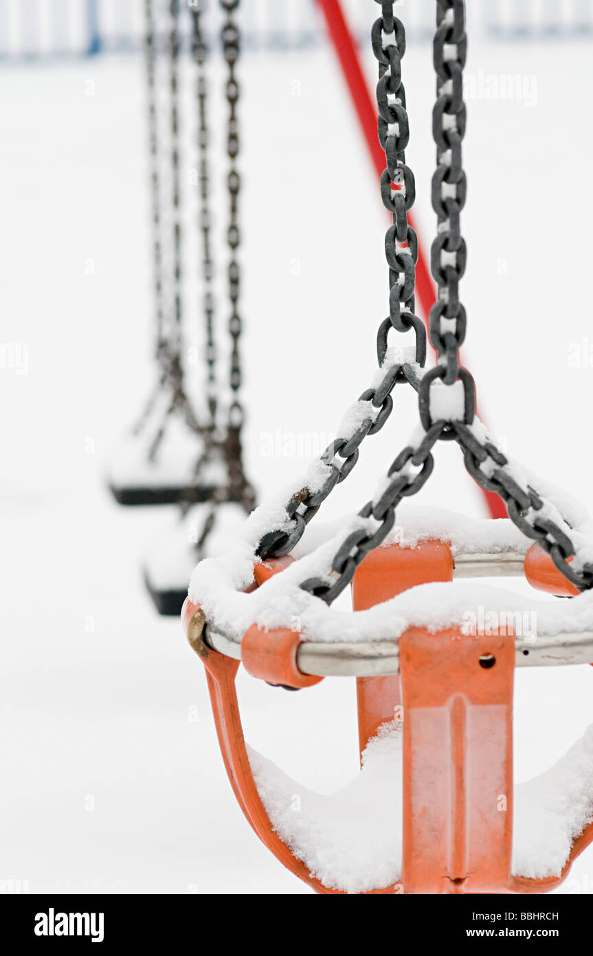 a swing covered with snow on a snowy day in a childrens playground in ...