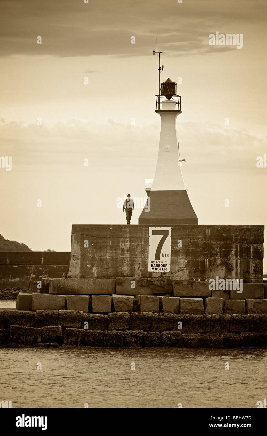 A beacon light stand guard at the end of the breakwater designating the ...