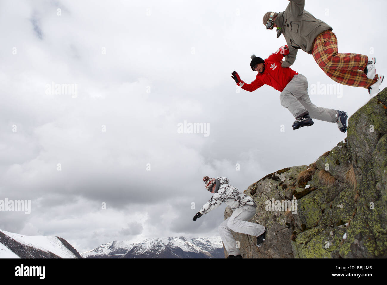 Skiers jump off a cliff into the fresh snow below, for fun, in the ski ...