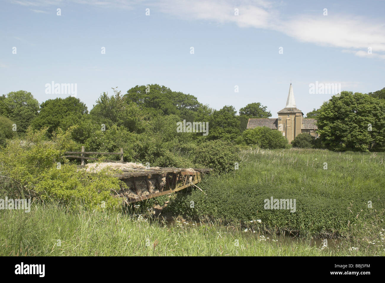 A dilapidated bridge over the River Adur with the church of St George ...