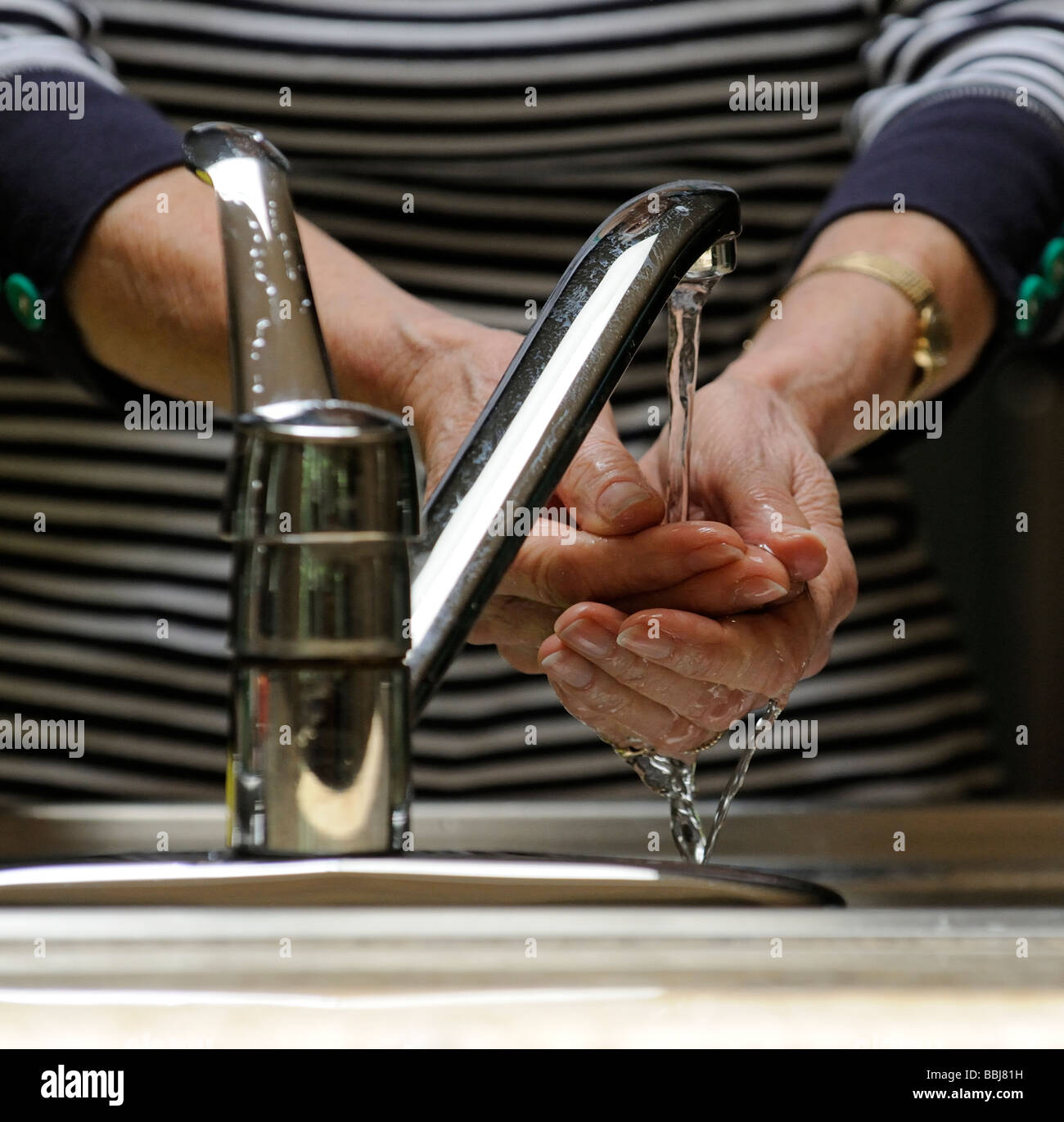 Woman washing hands under running water from the kitchen tap Stock ...
