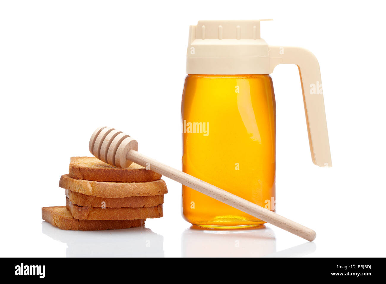Honey pitcher wooden drizzler and pile of toasts reflected on white ...