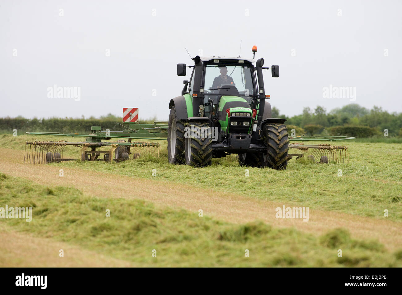 Deutz tractor with silage rake making silage to feed dairy cows in the ...