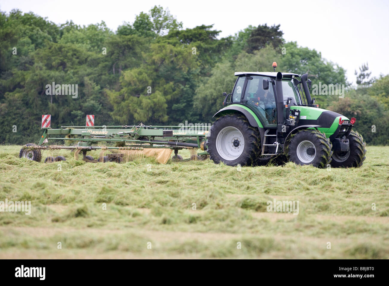 Deutz tractor with silage rake making silage to feed dairy cows in the ...