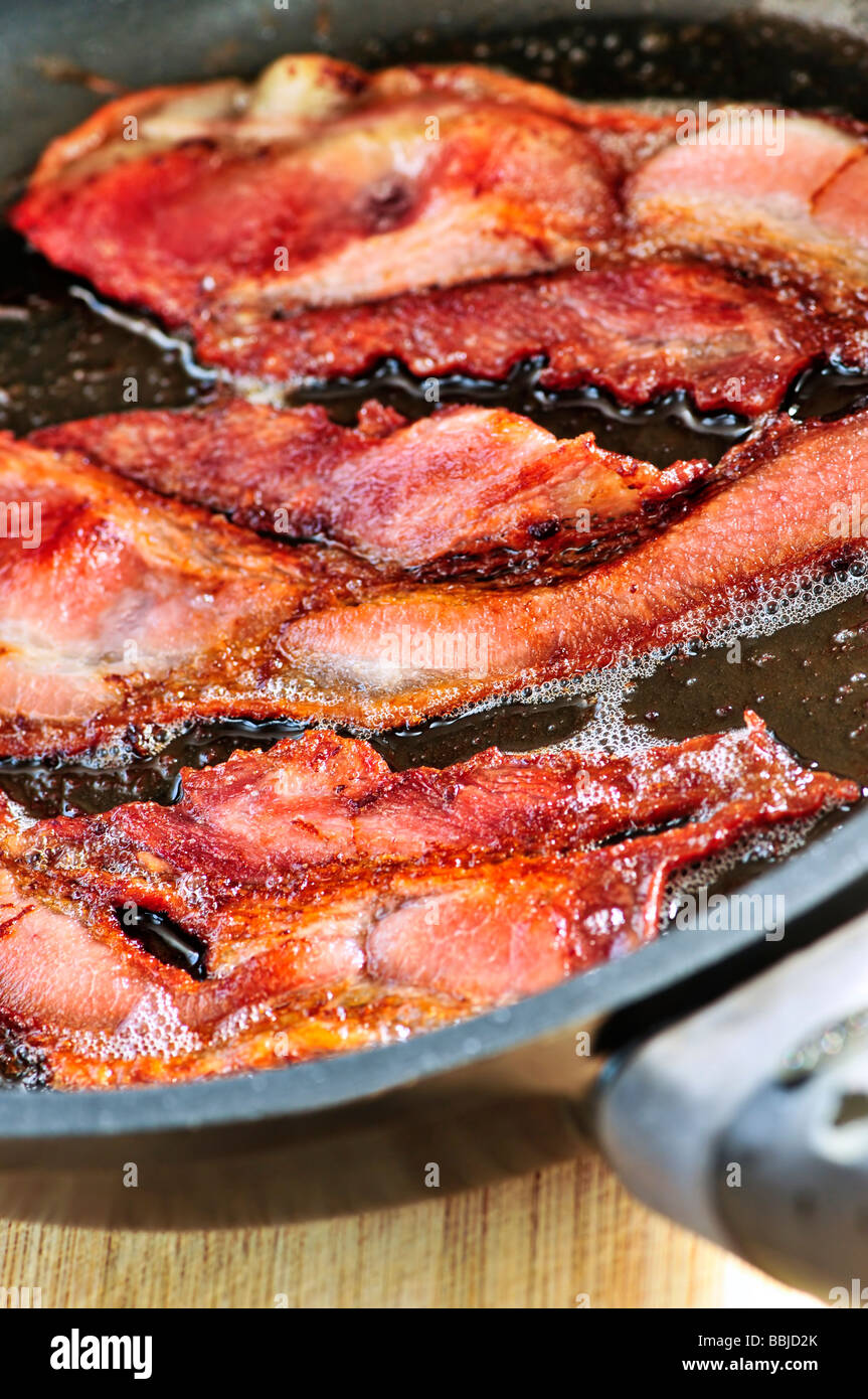 Bacon strips sizzling on a frying pan Stock Photo - Alamy