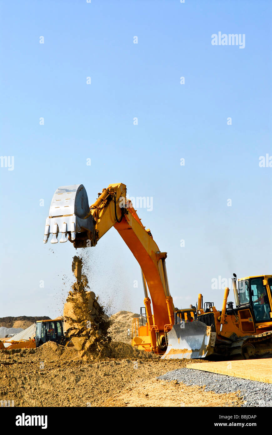 Yellow bulldozer machines digging and moving earth at construction site ...