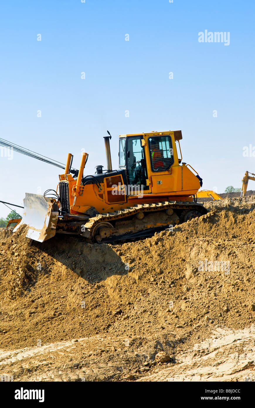 Yellow bulldozer machines digging and moving earth at construction site ...