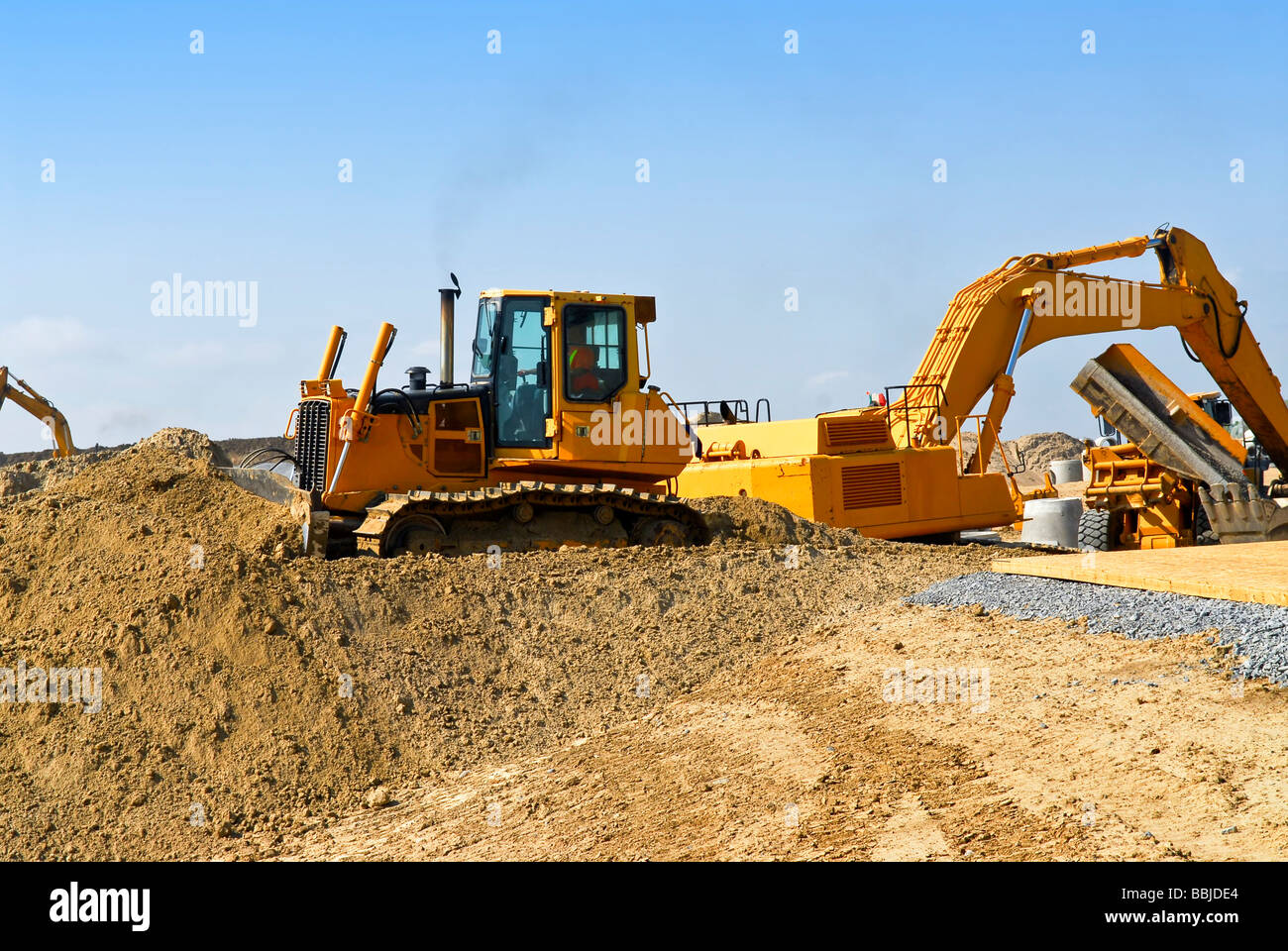 Yellow bulldozer machines digging and moving earth at construction site ...